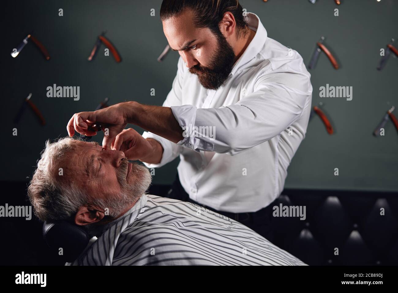 experienced stylist doing his best, close up side view photo. barbing ...