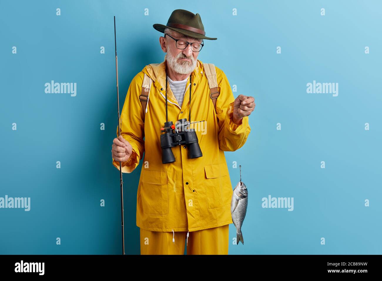 man is unhappy as he has poor catch, old man holding rod and looking at ...