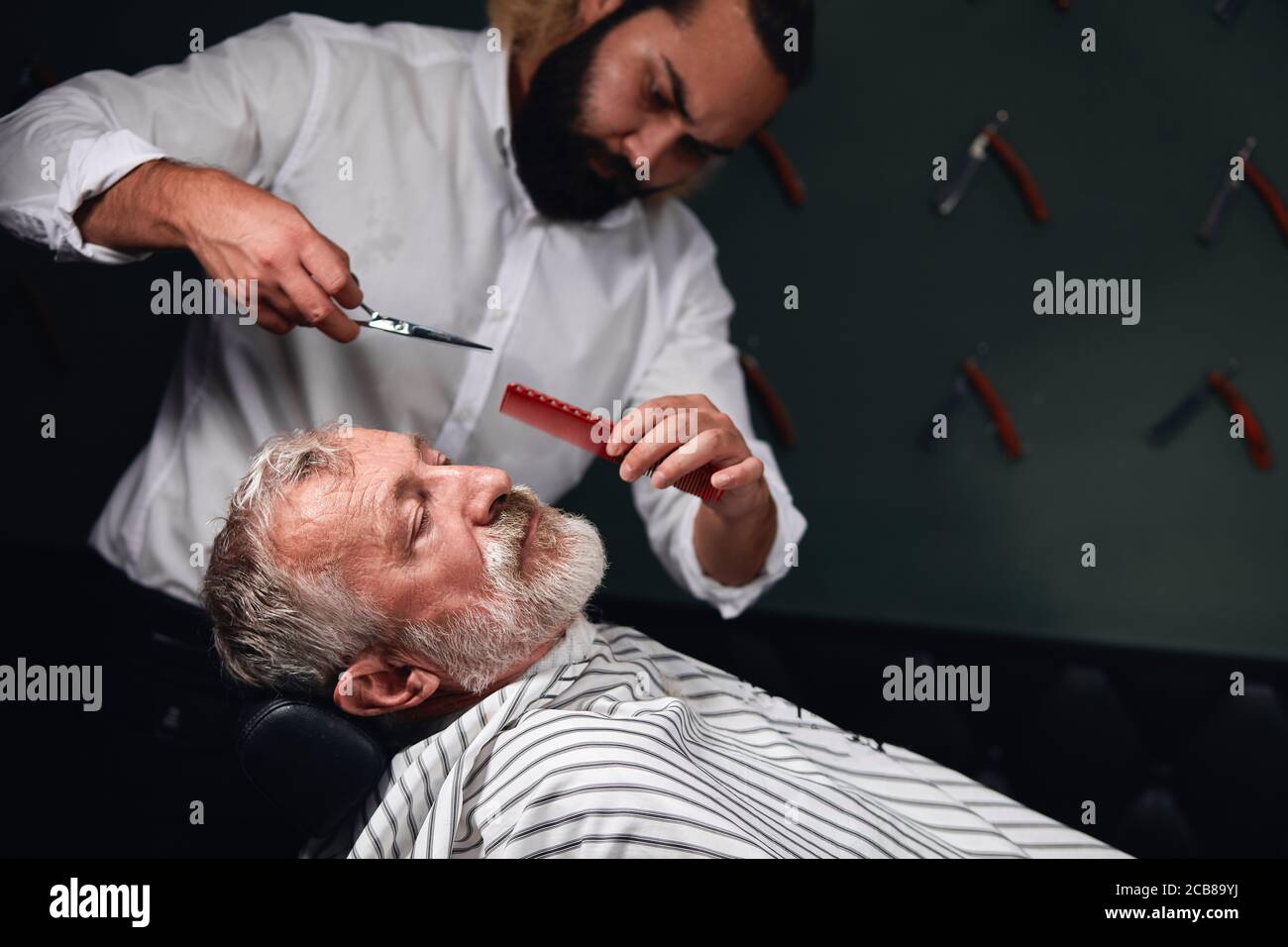 young professional barber working with tools in the dark room, close up ...