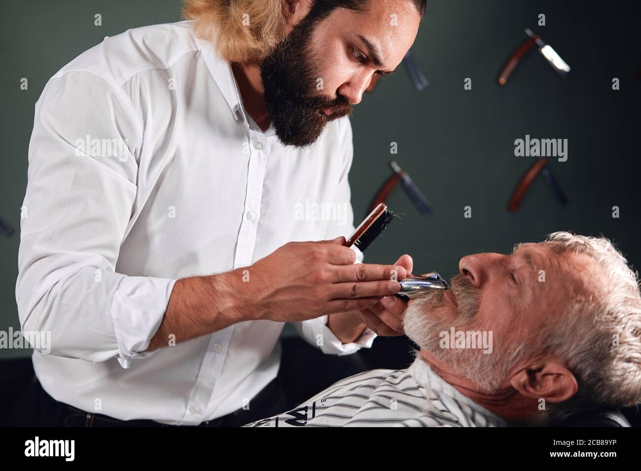 handsome stylist makes hairstyle for old man. close up side view photo ...