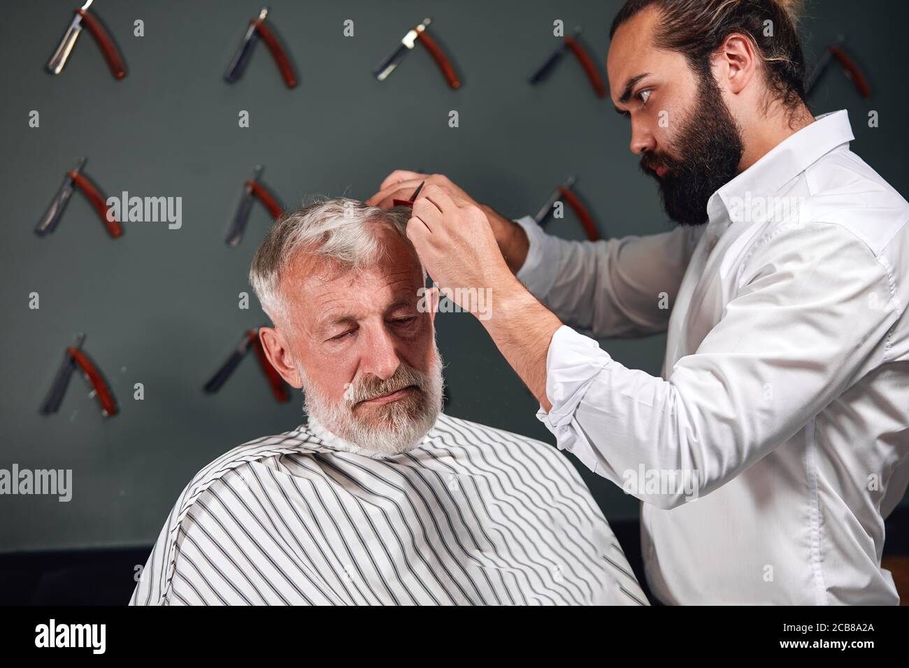 Active retired old man getting haircut by experienced barber in barber ...