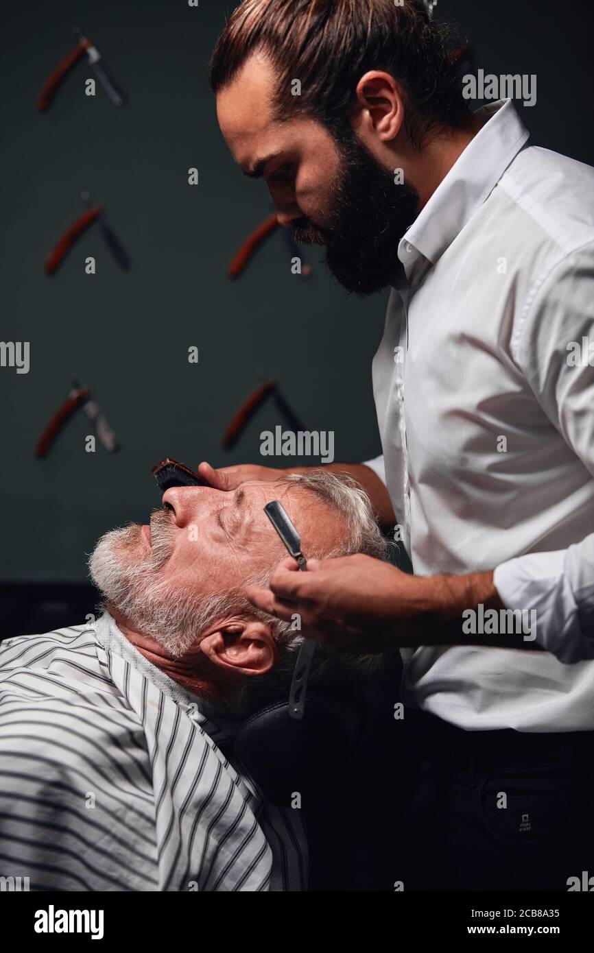 barber preparing client's face for shaving, trimming. close up side ...