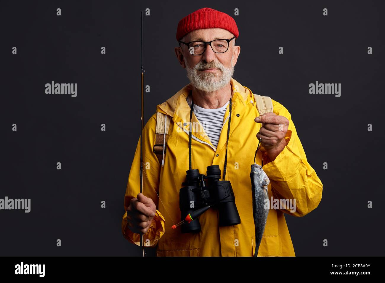 Bearded old attractive man with serious expression angling fish in pond ...