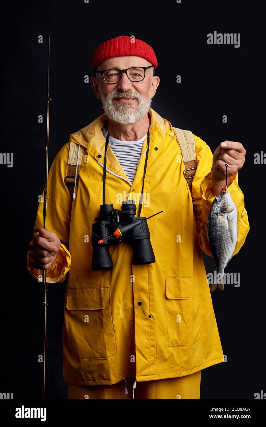 positive attractive man in yellow stylish coat and red cap boasting ...