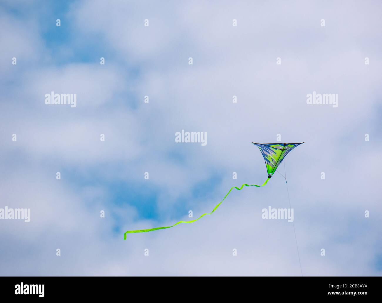 Colourful kite flying high in a sunny sky with white clouds Stock Photo ...