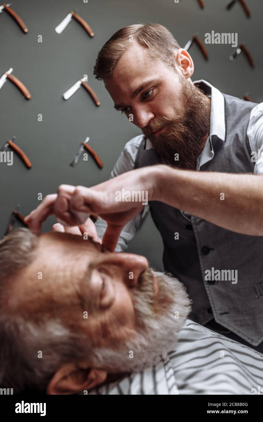 Close Up Shot Of Professional Man S Hair Stylist Shaving Old Man In A