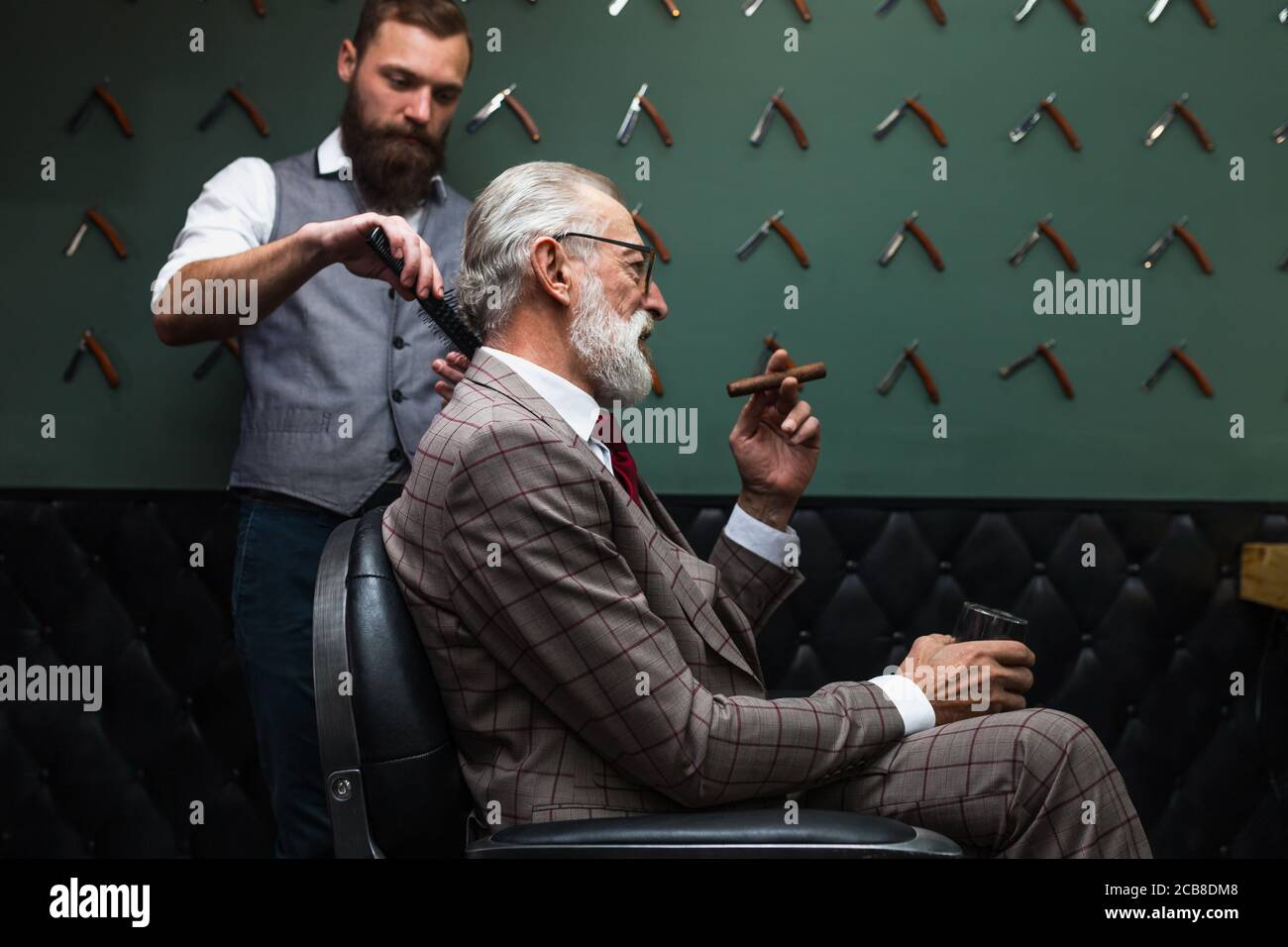 Barber making male haircut. Hairdresser cutting hair of his rich client ...
