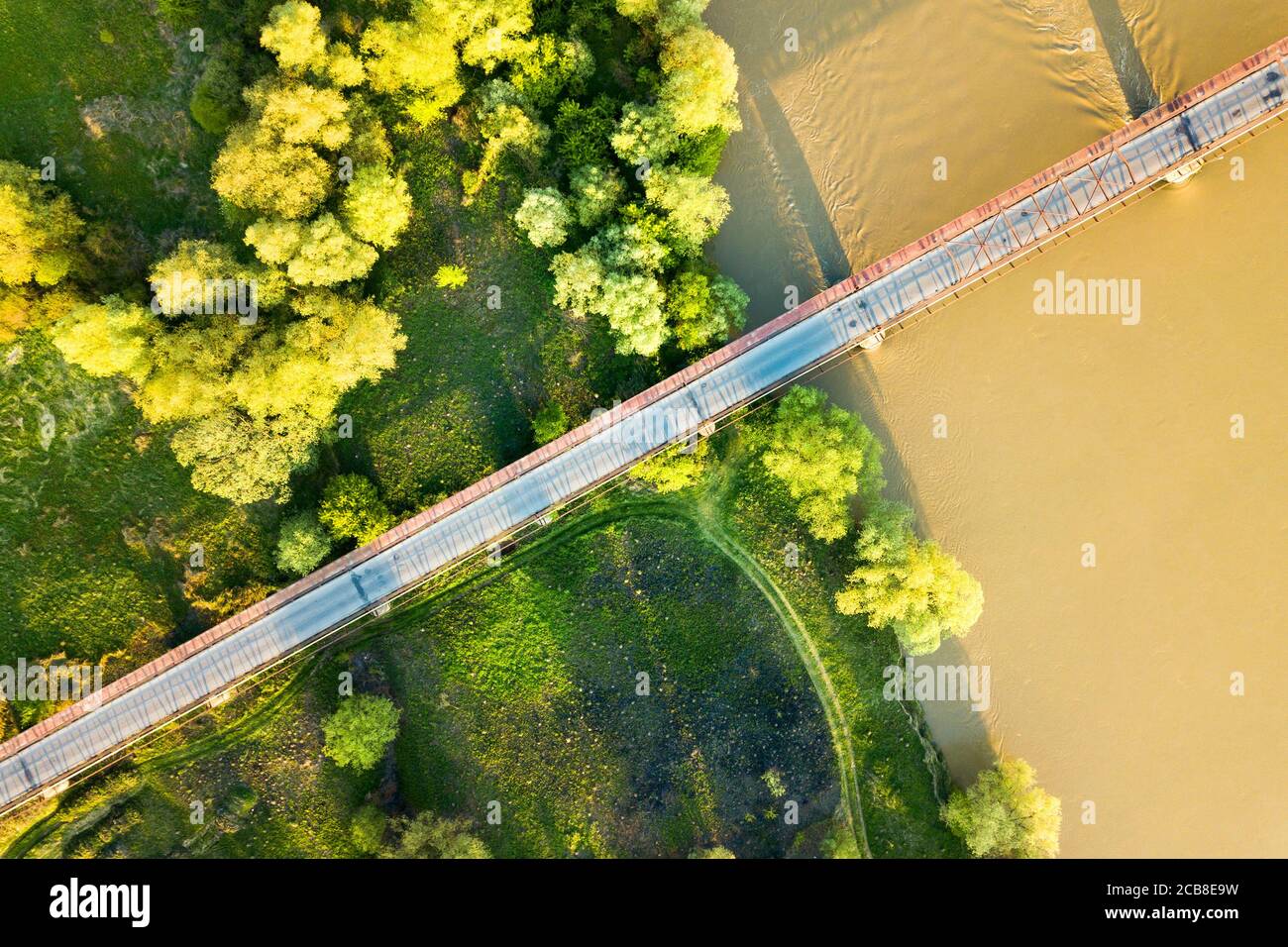 Aerial view of a narrow road bridge stretching over muddy wide river in ...