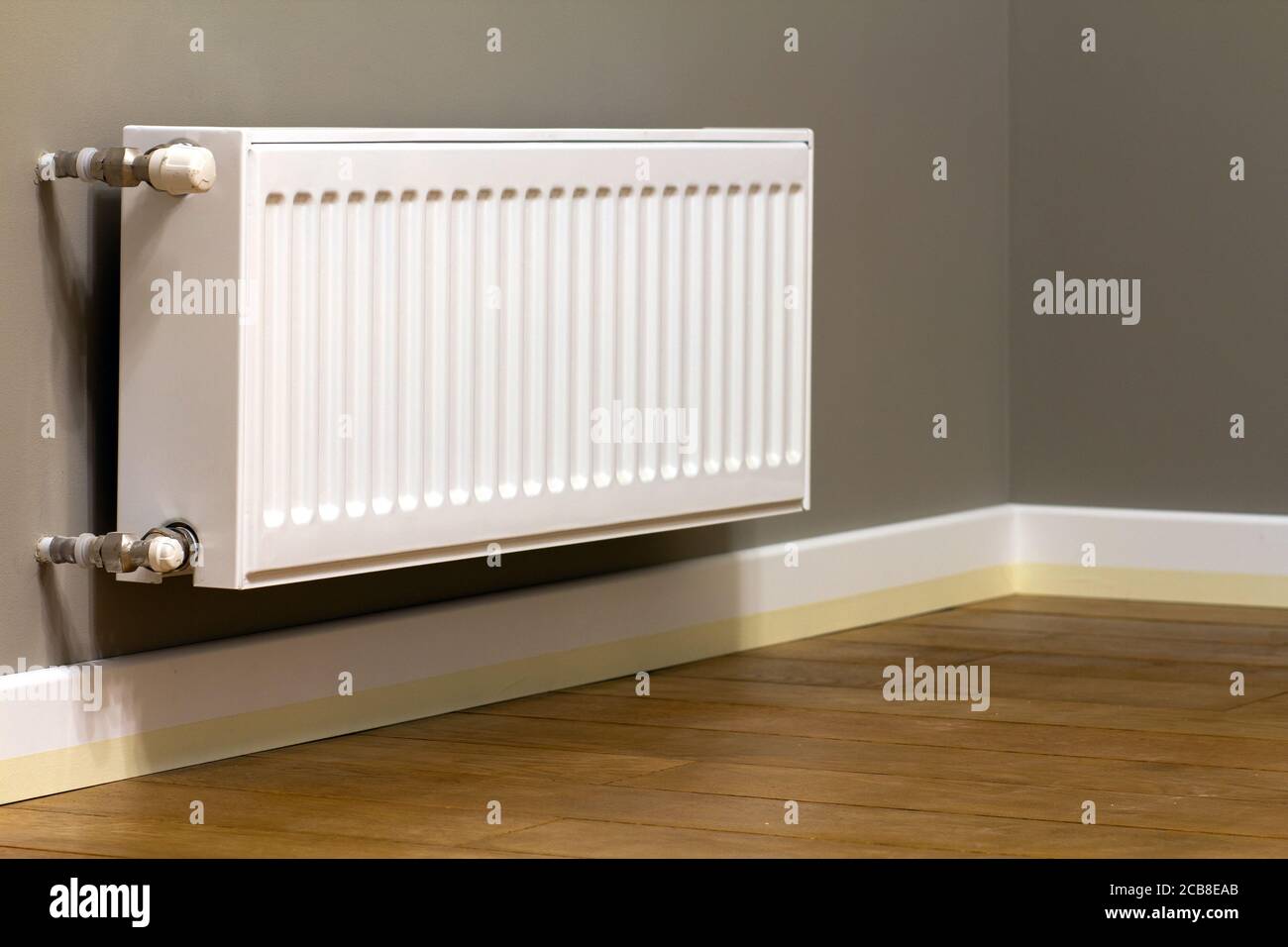 White metal heating radiator mounted on gray wall inside a room Stock ...