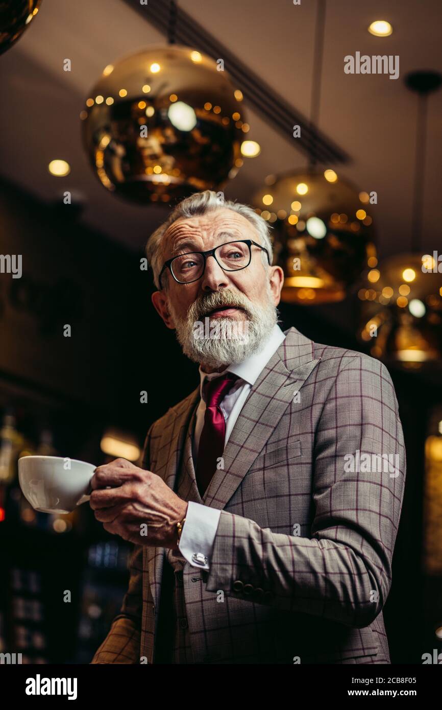 Portrait of surprised senior businessman in drinking coffee near bar ...