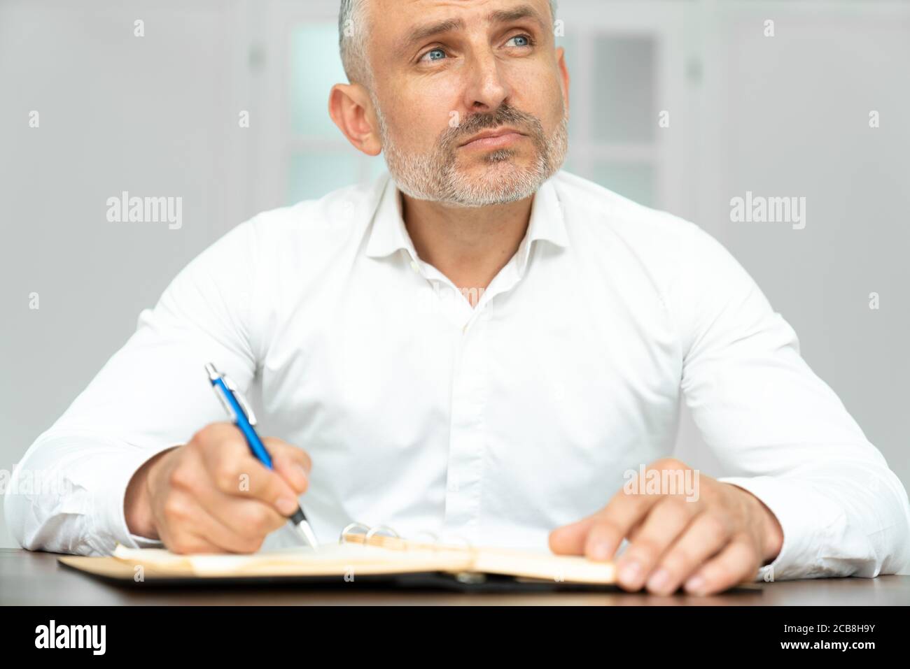 From below of excited charismatic ethnic guy in white shirt with pen in ...