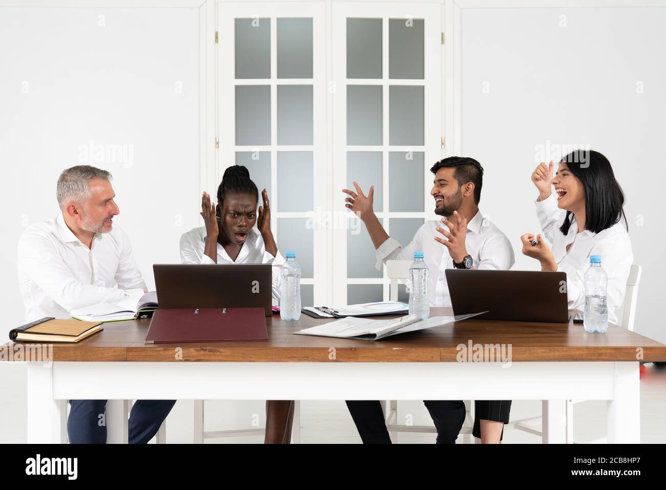 Office workers gather around a table to do research and implement new ...