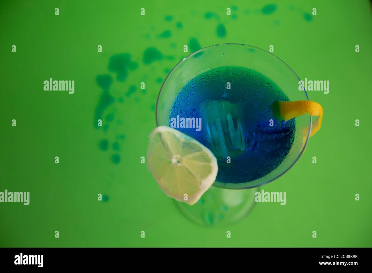 Top view of a glass of blue lagoon cocktail with lemon on a green ...