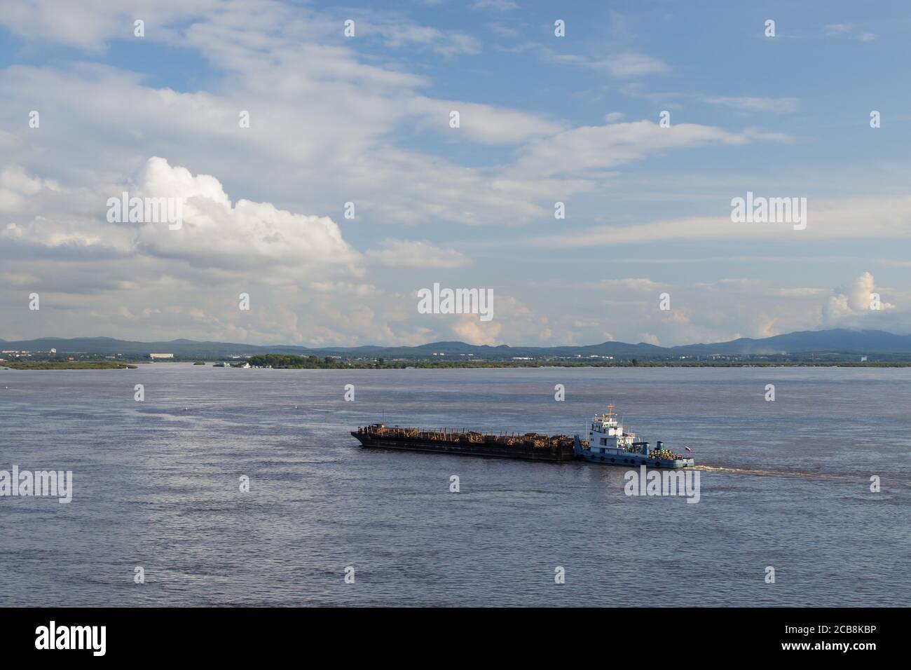 On the Amur River, a tugboat pushes a barge with logs Stock Photo - Alamy