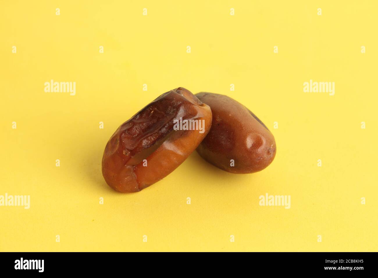 High angle shot of two dried dates isolated on a yellow surface Stock ...