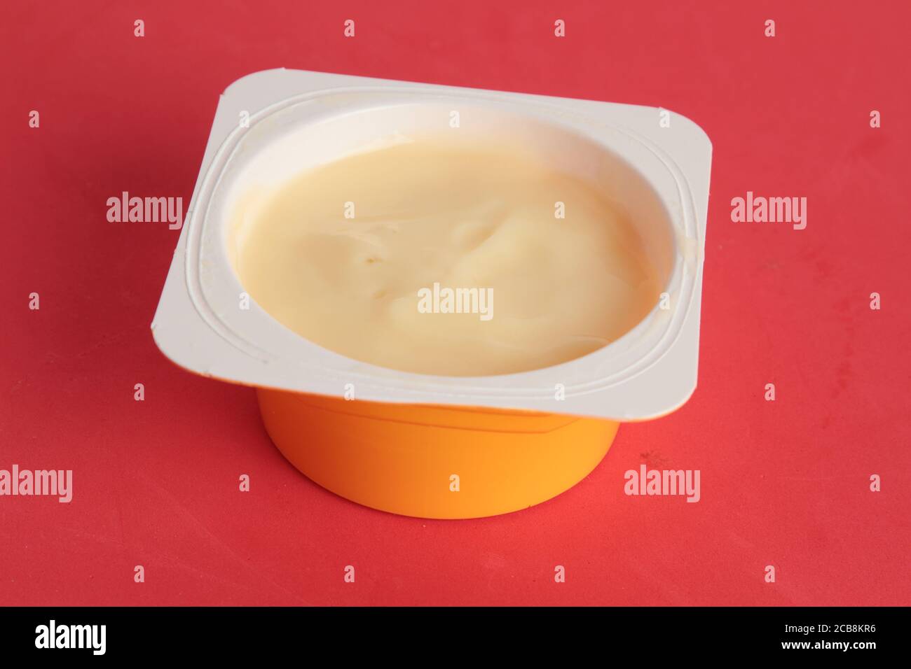 Closeup shot of custard in a plastic container on a red surface Stock ...