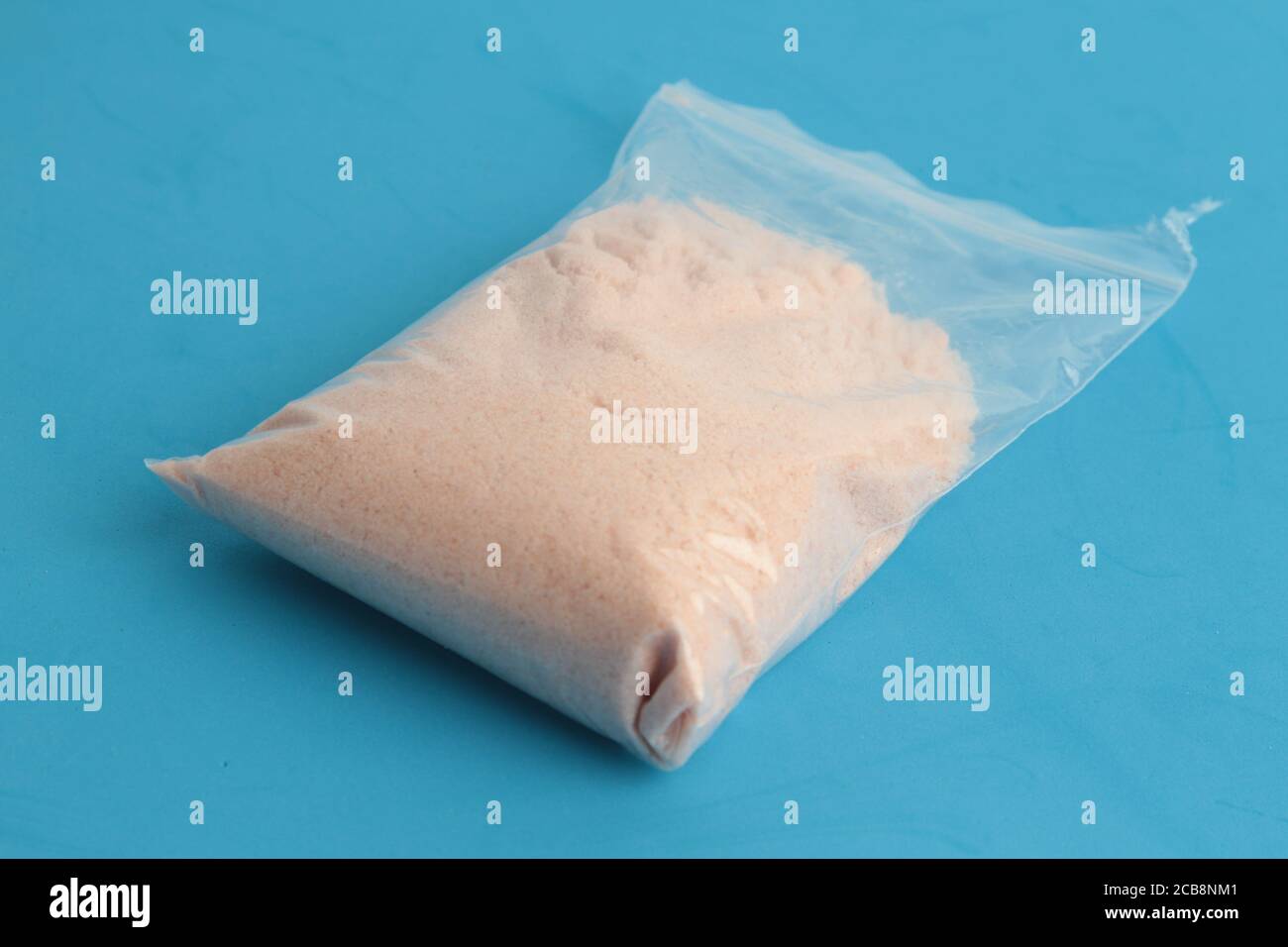 Closeup shot of sand in a plastic bag on a blue surface Stock Photo - Alamy