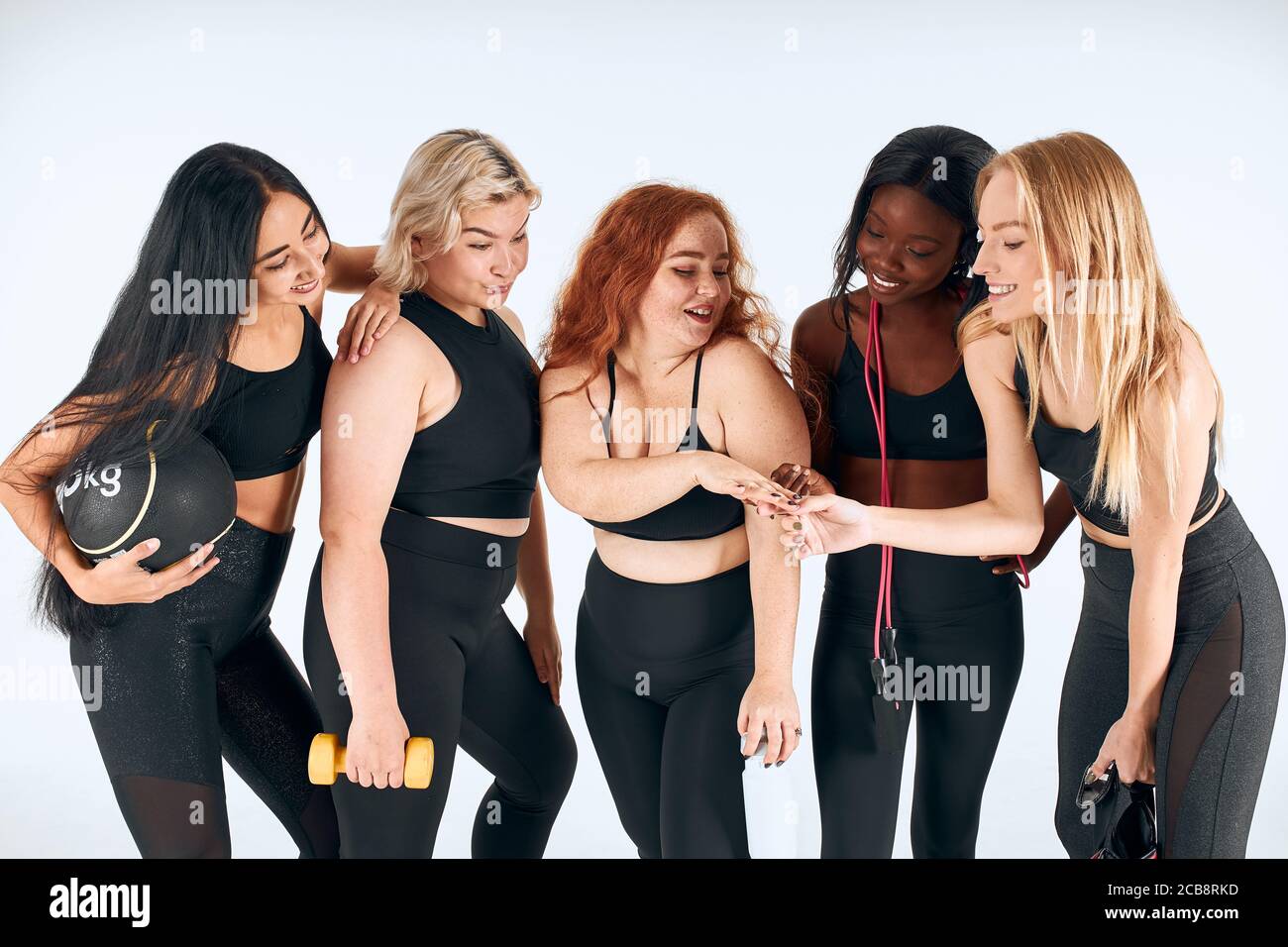 Five attractive girls stand together isolated over white background ...