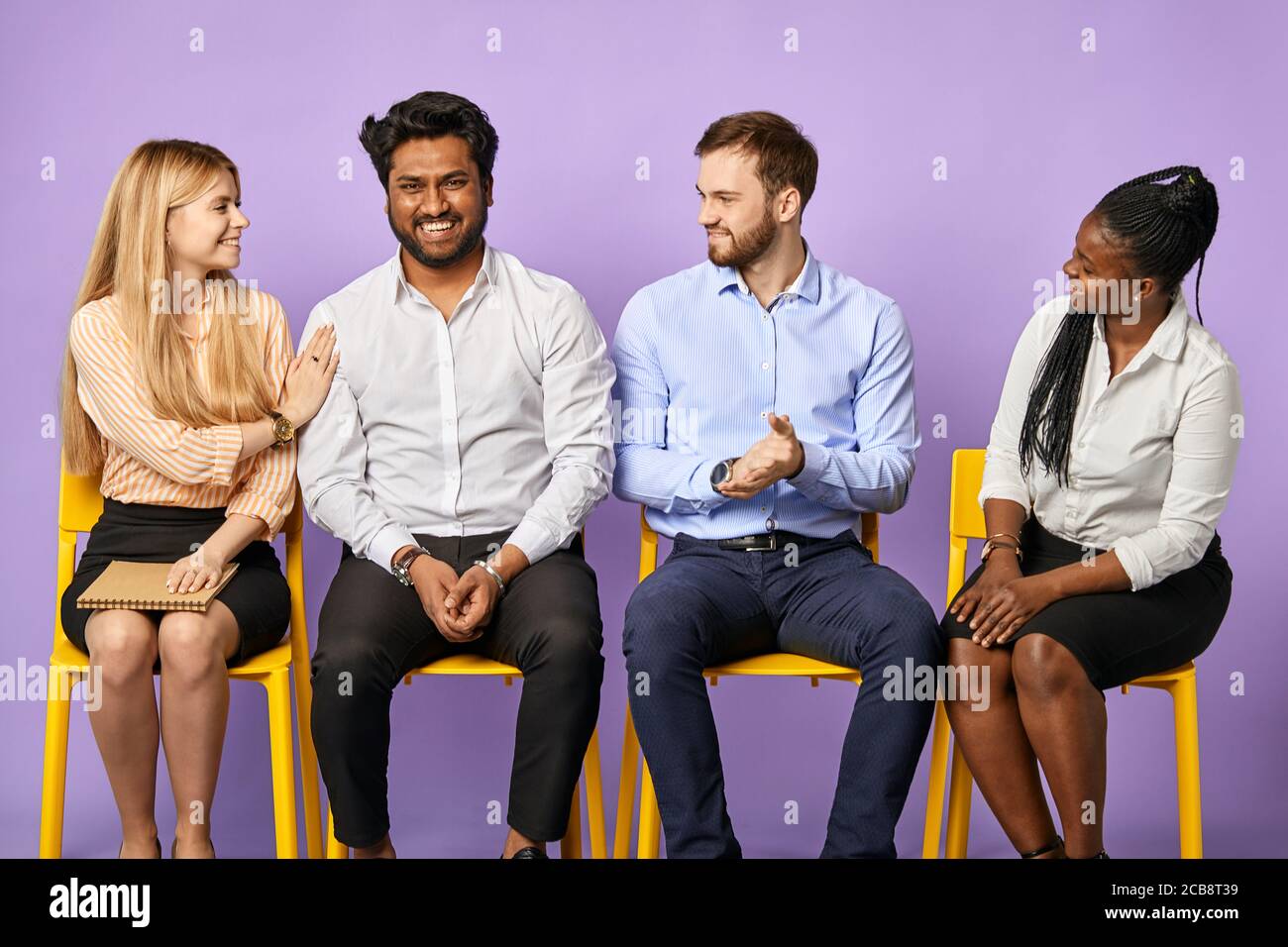 Multinational team smiling happily and congratulating their coworker ...