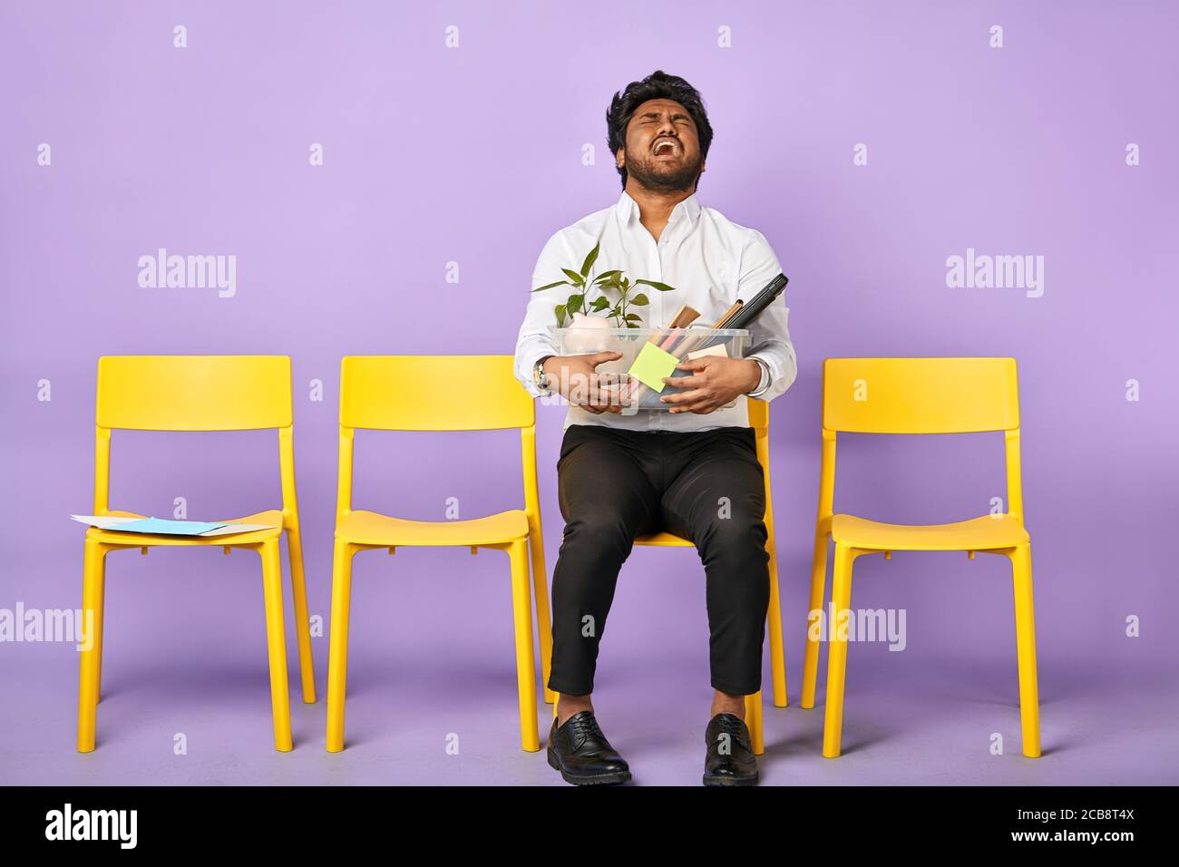 frustrated young dark-skinned man crying and holding box of personal ...