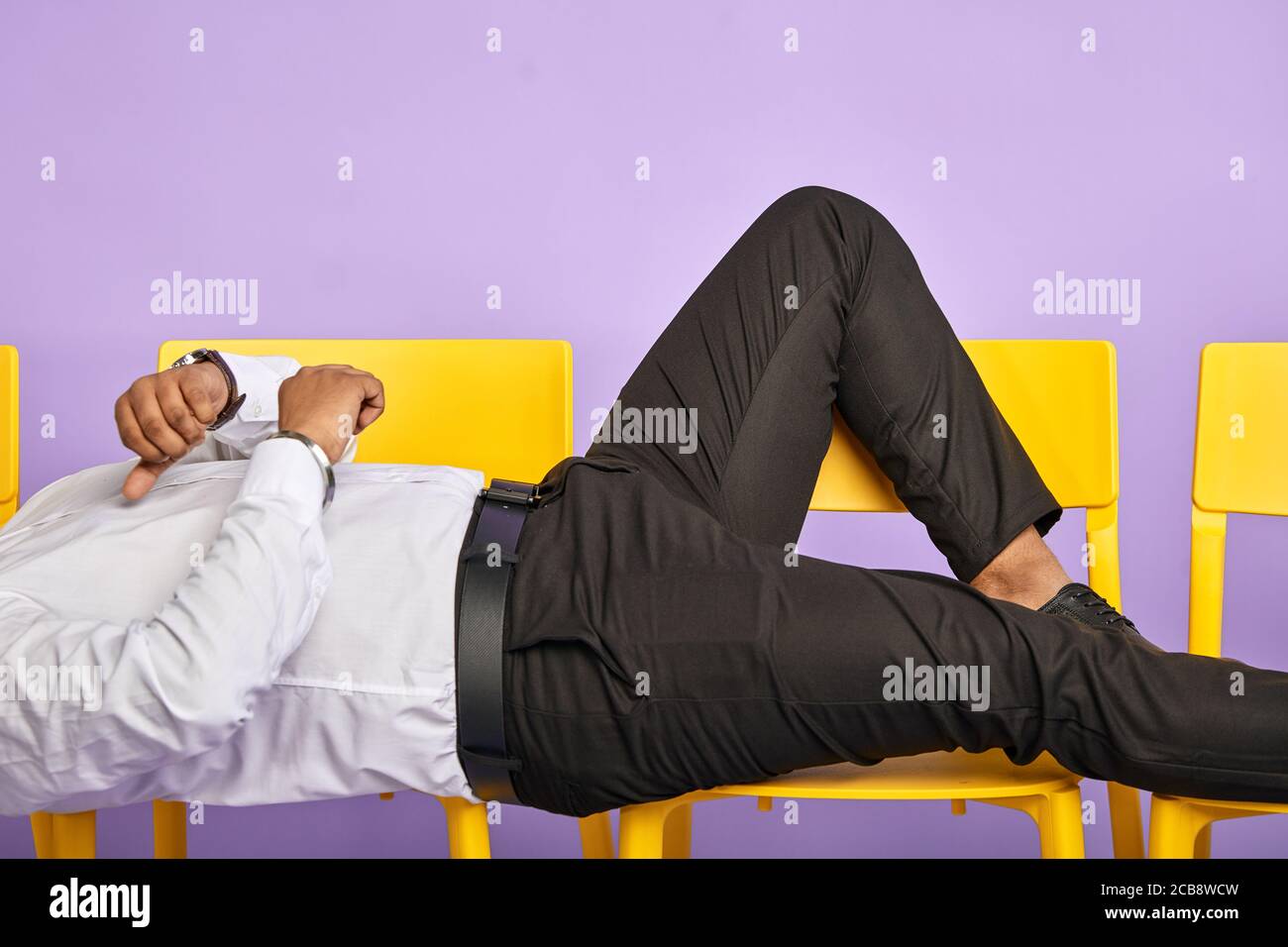 young man resting on chairs with crossed hands. Hands and legs close up ...