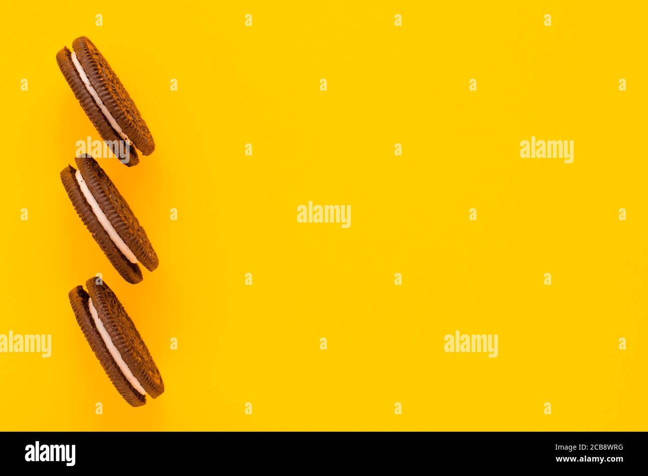 Sweet brown cookies with white cream inside on bright yellow background ...