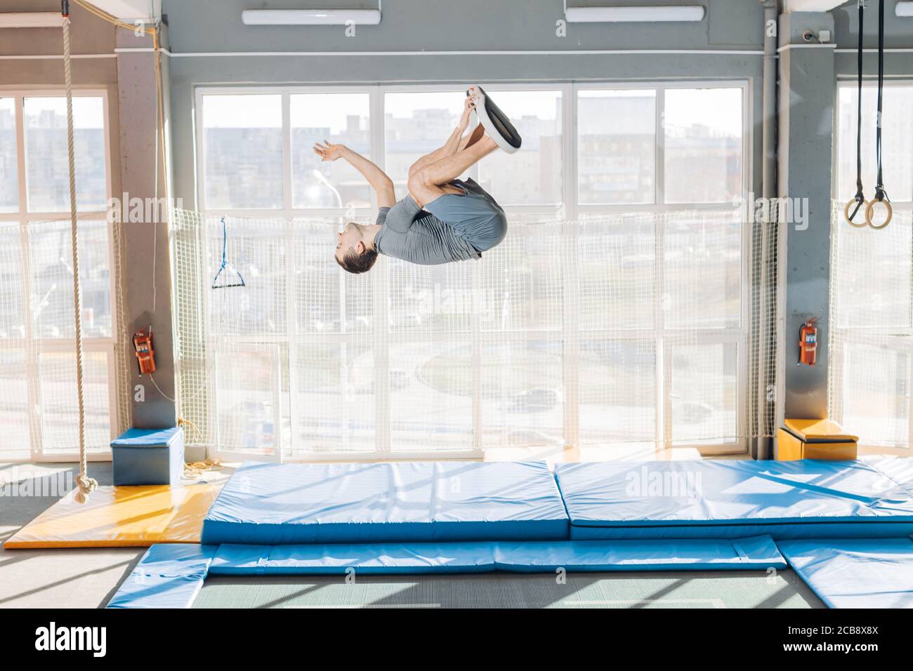 risky sport. young active man doing stints with board at gym. full ...