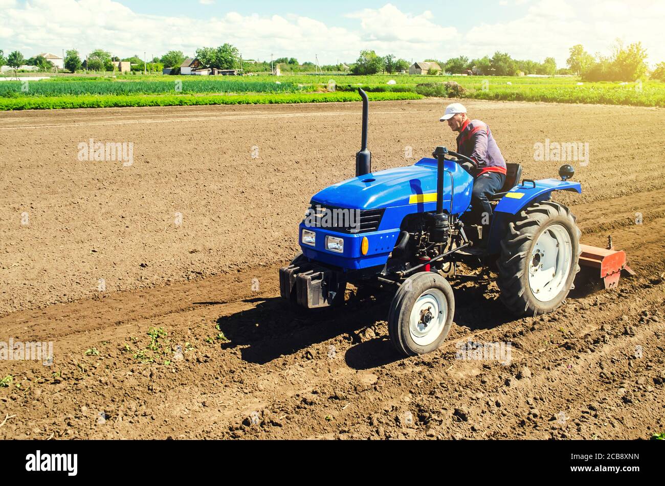 Farmer on a tractor with a milling machine processes loosens soil in ...