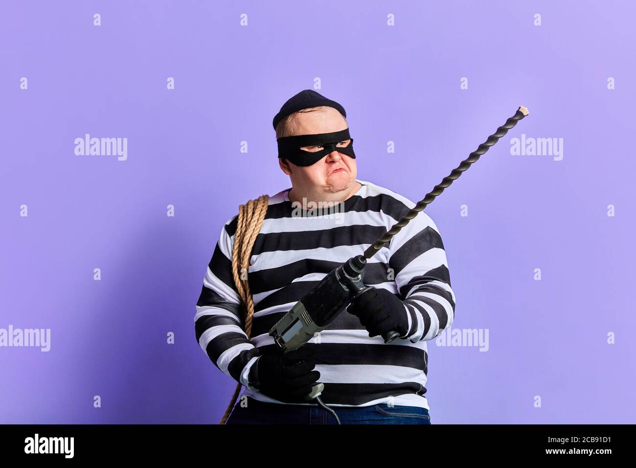 serious robber with a drilling machine makes illegal work. plump thief ...