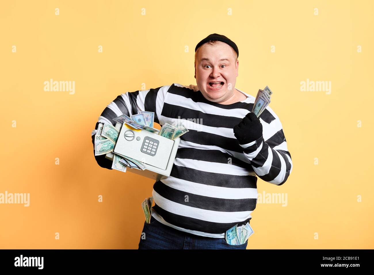 smiling positive criminal making boast of money. isolated yellow ...