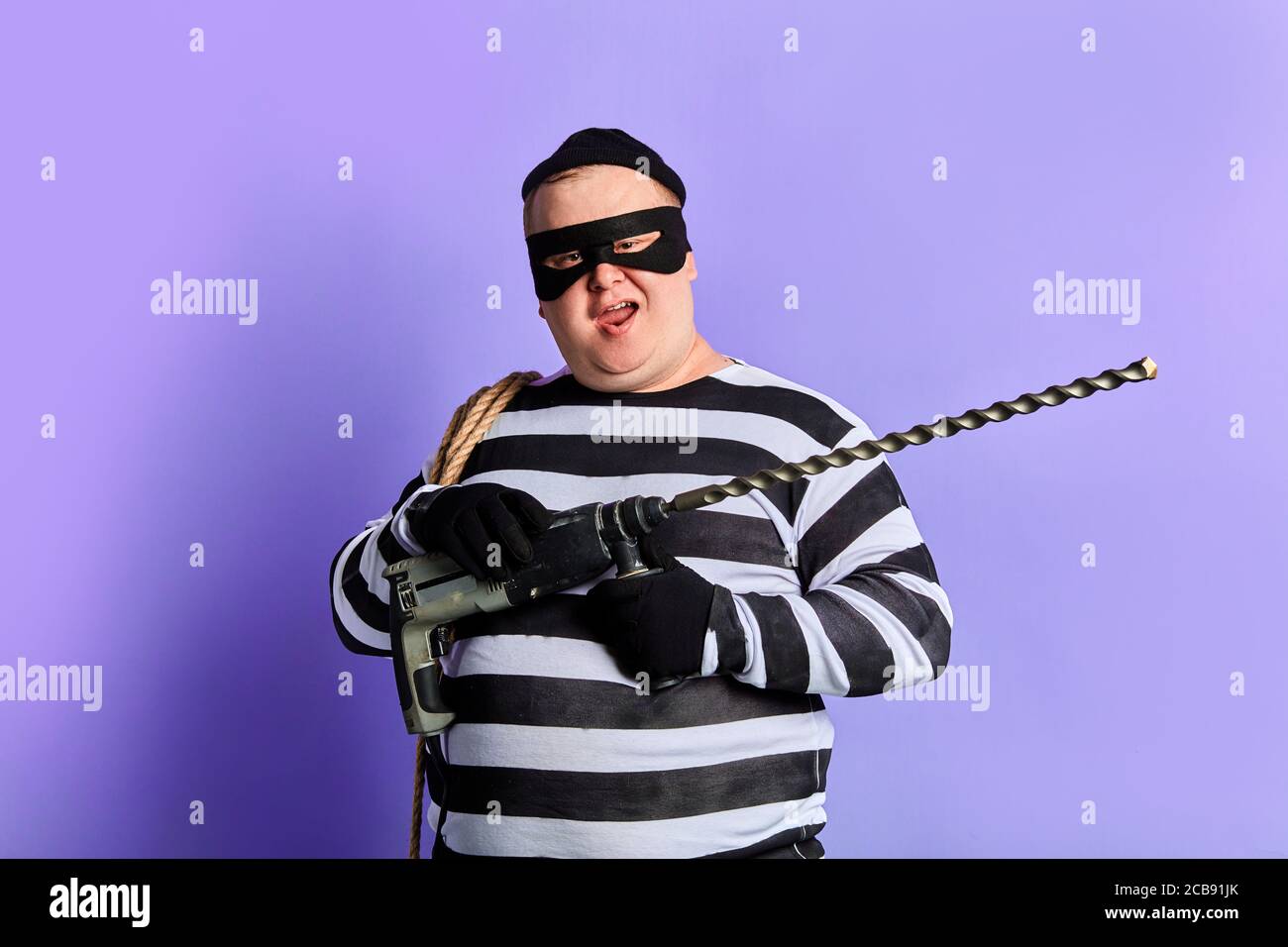 cheeful smiling prisoner using a drill to steal money, isolated blue ...