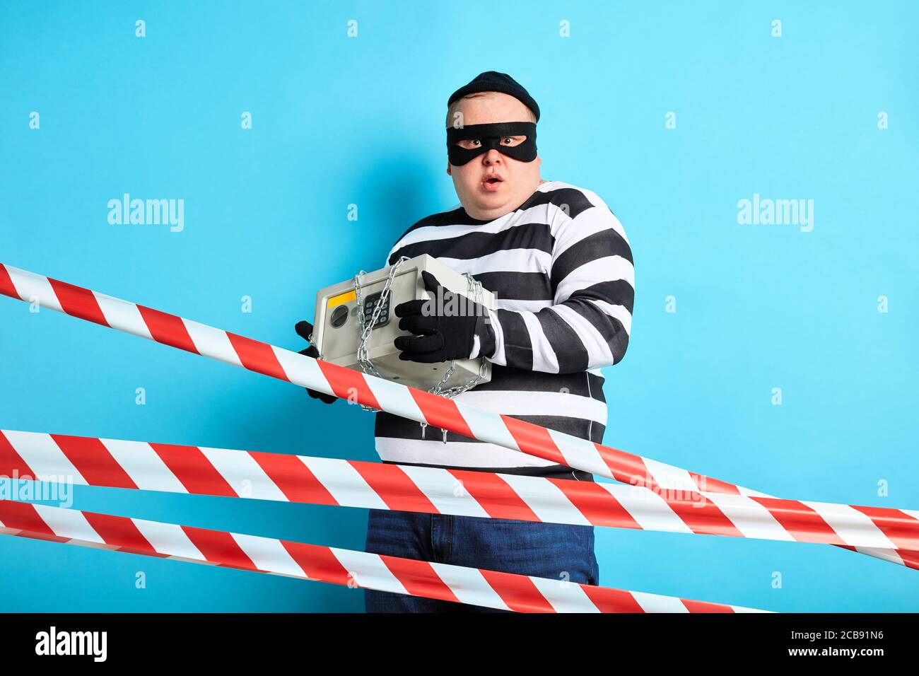 surprised scared man holding a safe while standing behind warning ...