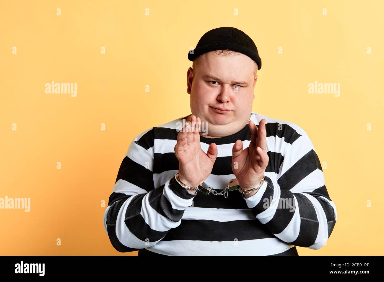 dangerous robber in handcuff posing to the camera. close up portrait ...