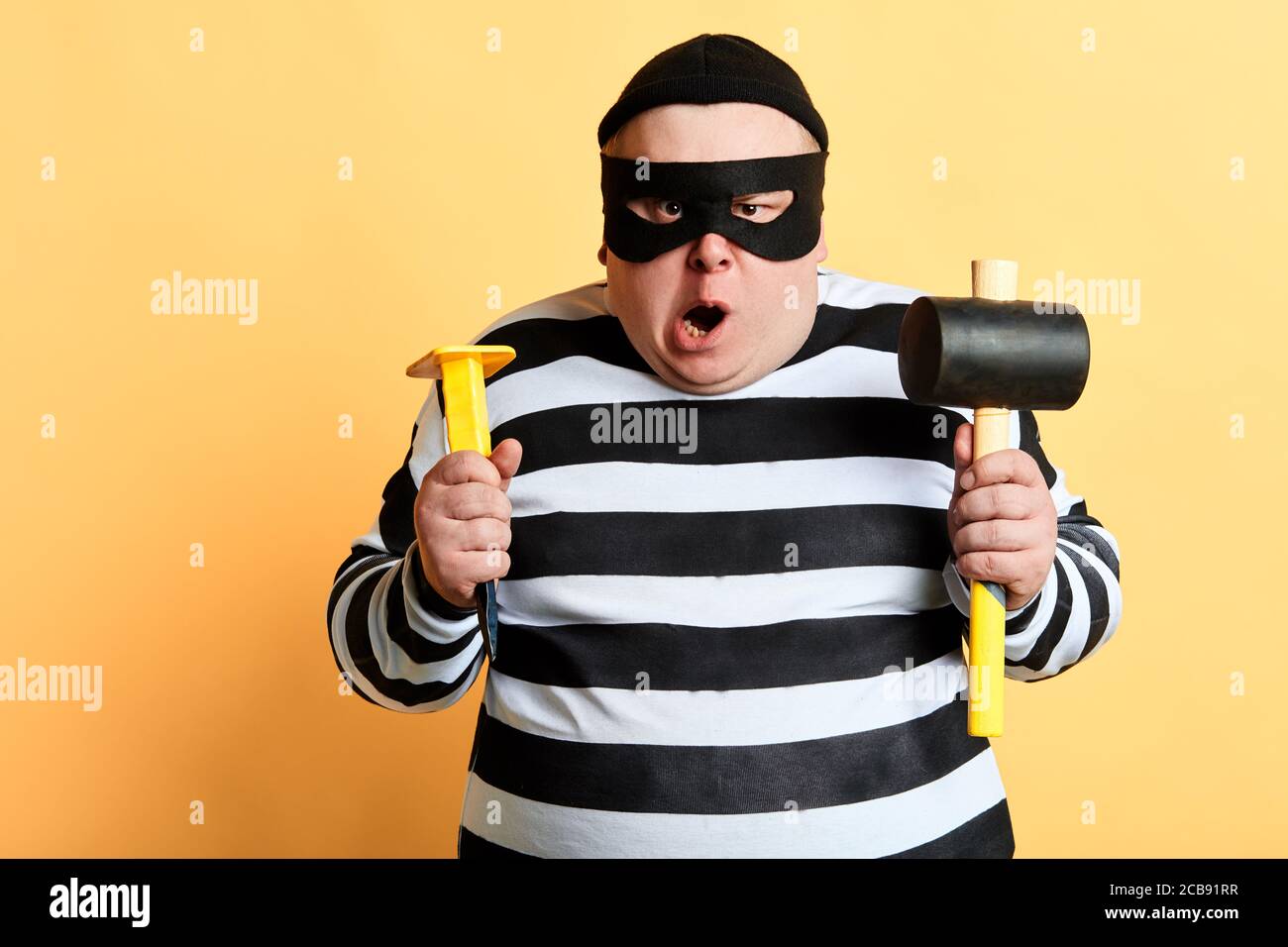 angry plump criminal in striped clothes preparing for crime, isolated ...