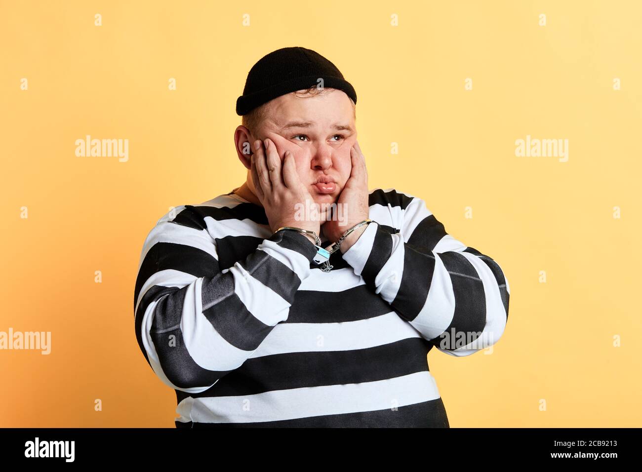 unhappy upset fat thief touching his cheek, thinking about his crime ...