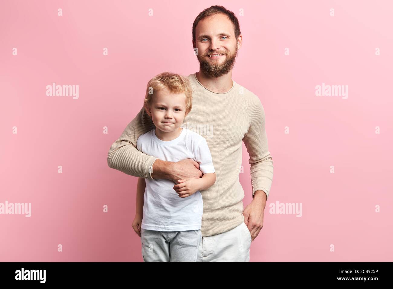 Happy daddy hugging his child, isolated pink background, studio shot ...