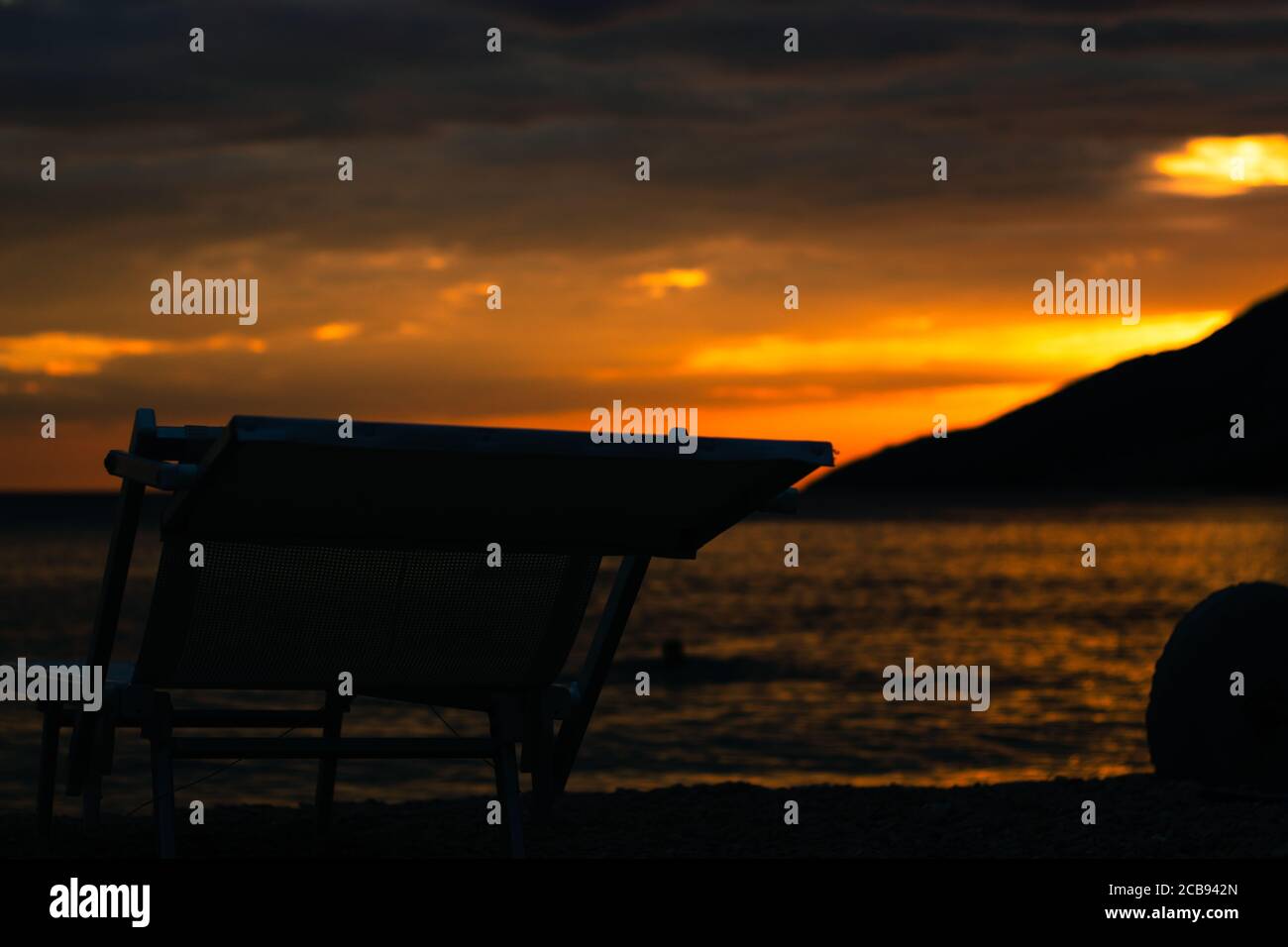 Late bright orange sunset on the Zlatni Rat beach in Bol. Dark outline ...