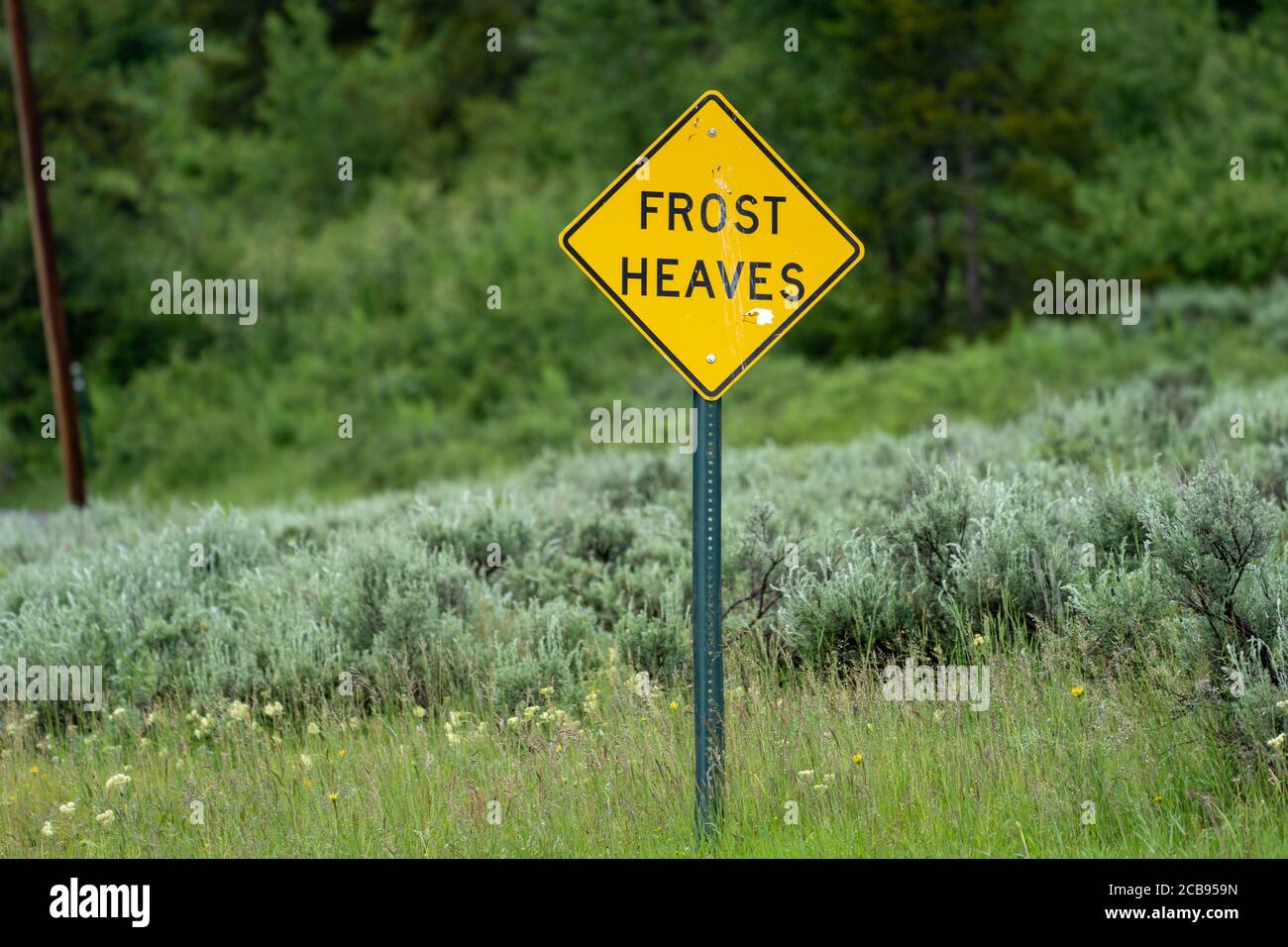 Sign warning drivers of frost heaves in the road Stock Photo - Alamy