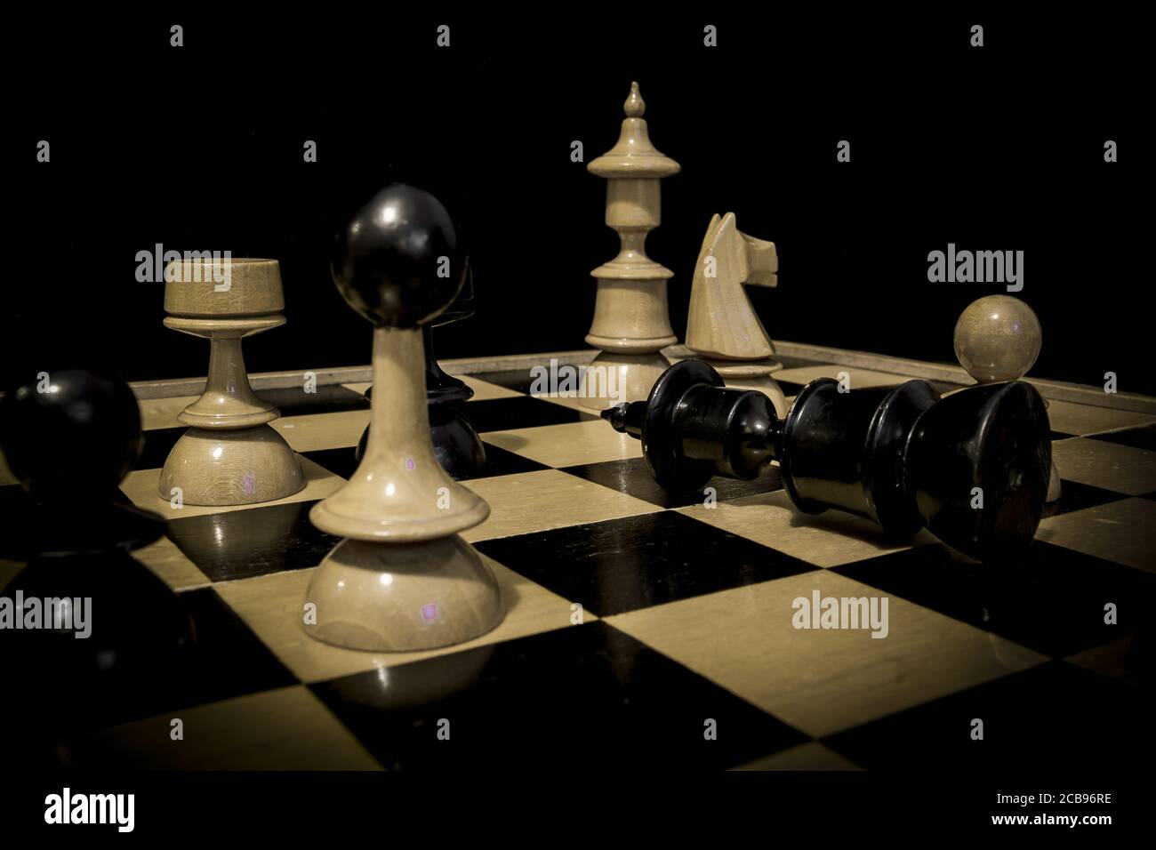 Fallen king chess piece surrounded by chess pieces on a chess board ...