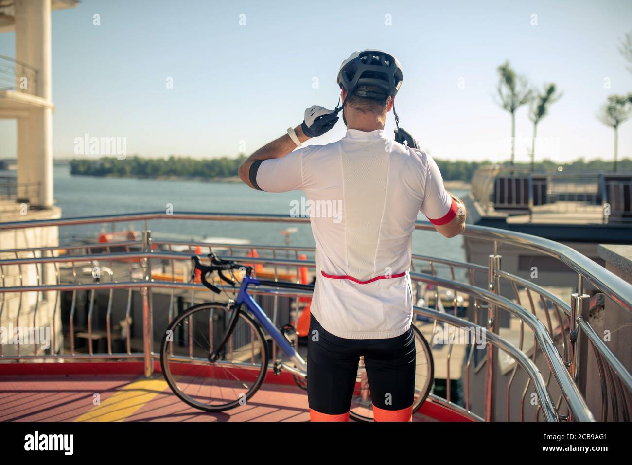 Man putting bicycle helmet standing with his back Stock Photo - Alamy