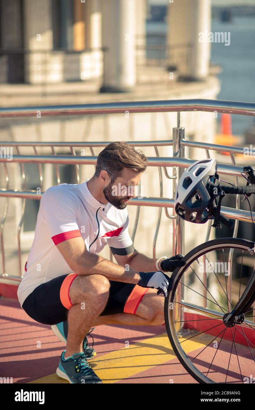 Cyclist crouched near wheel of his bike Stock Photo - Alamy