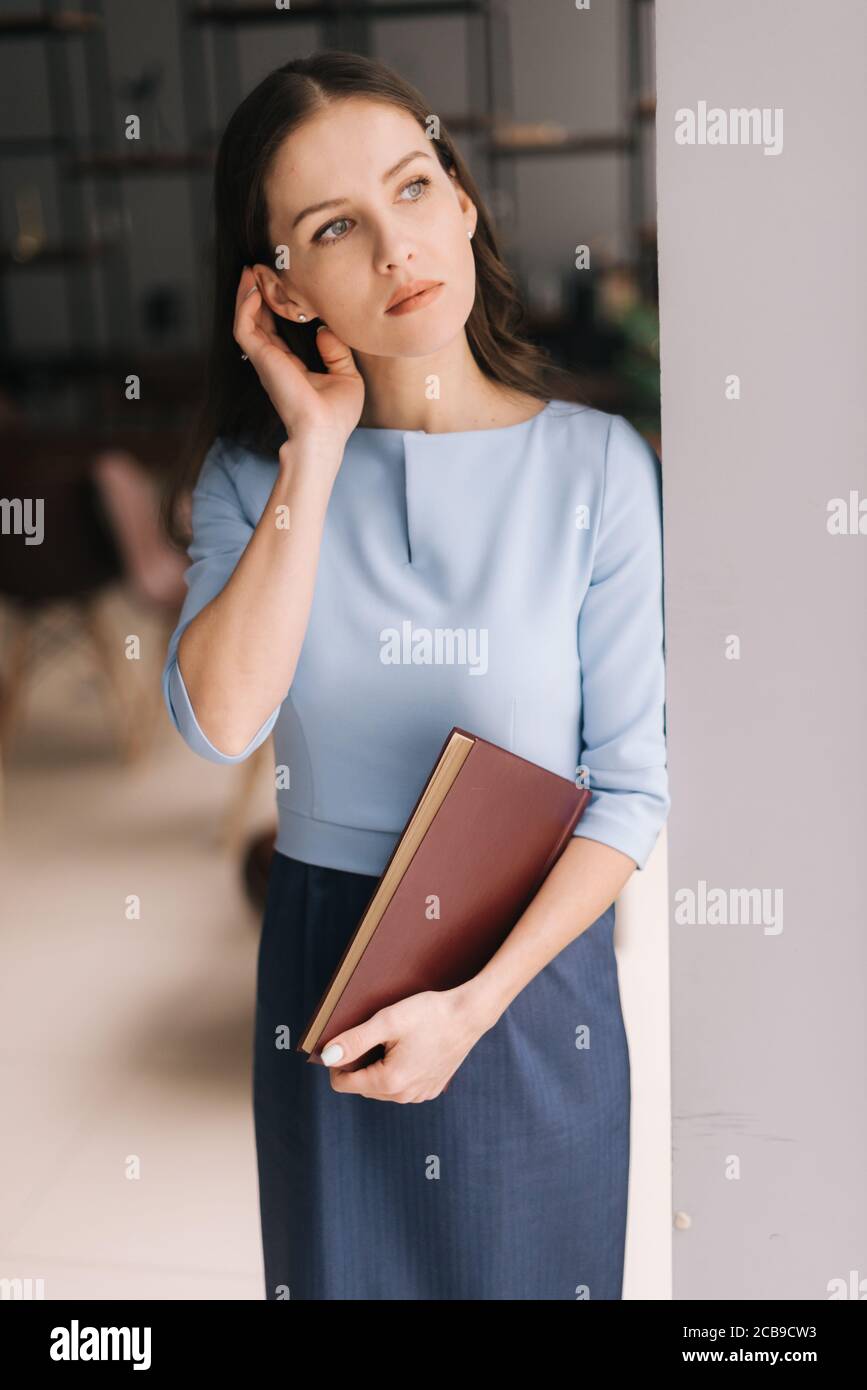 Beautiful young business woman holding file folder while standing near ...