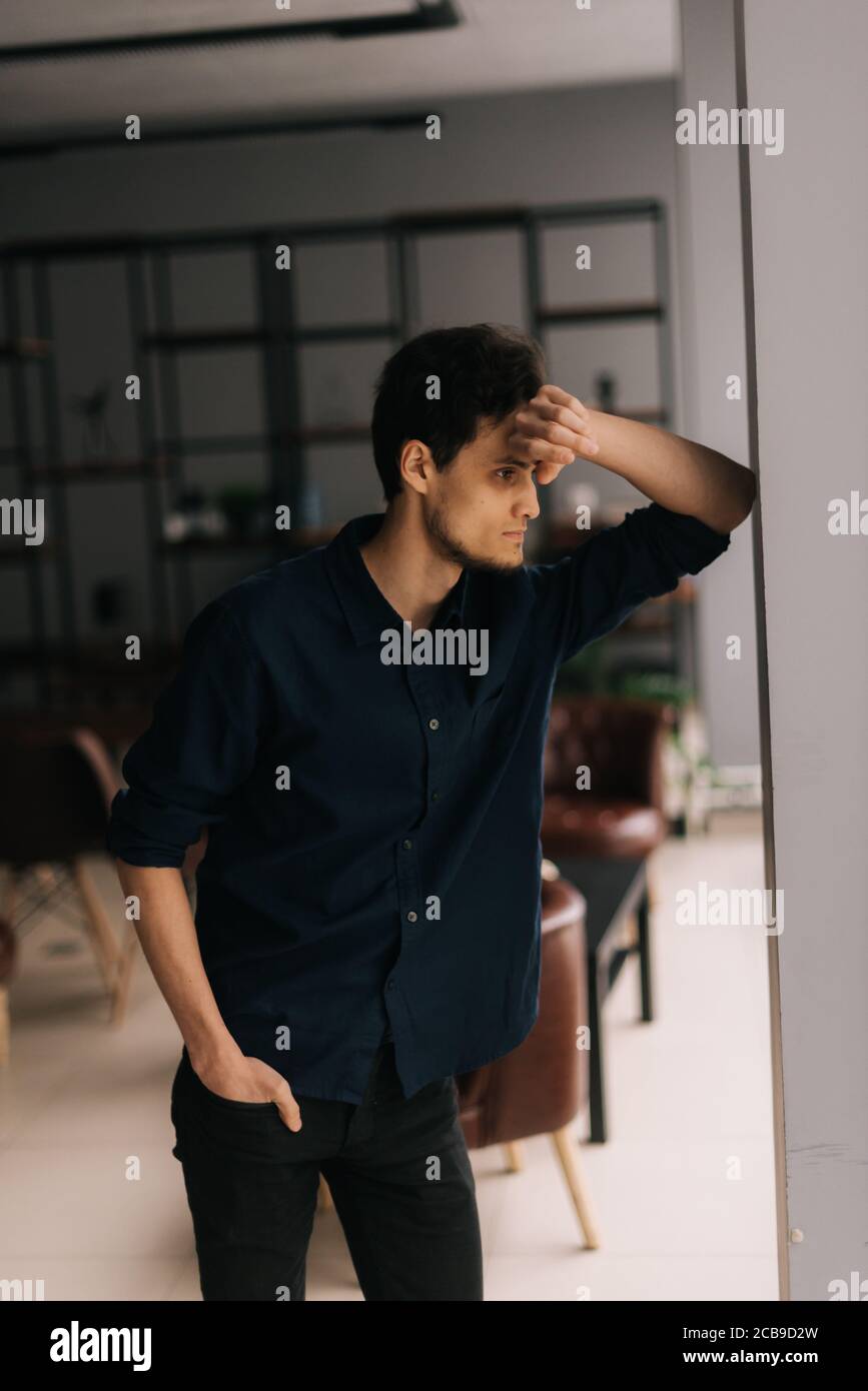 Handsome upset young man with pensive stress expression standing near ...