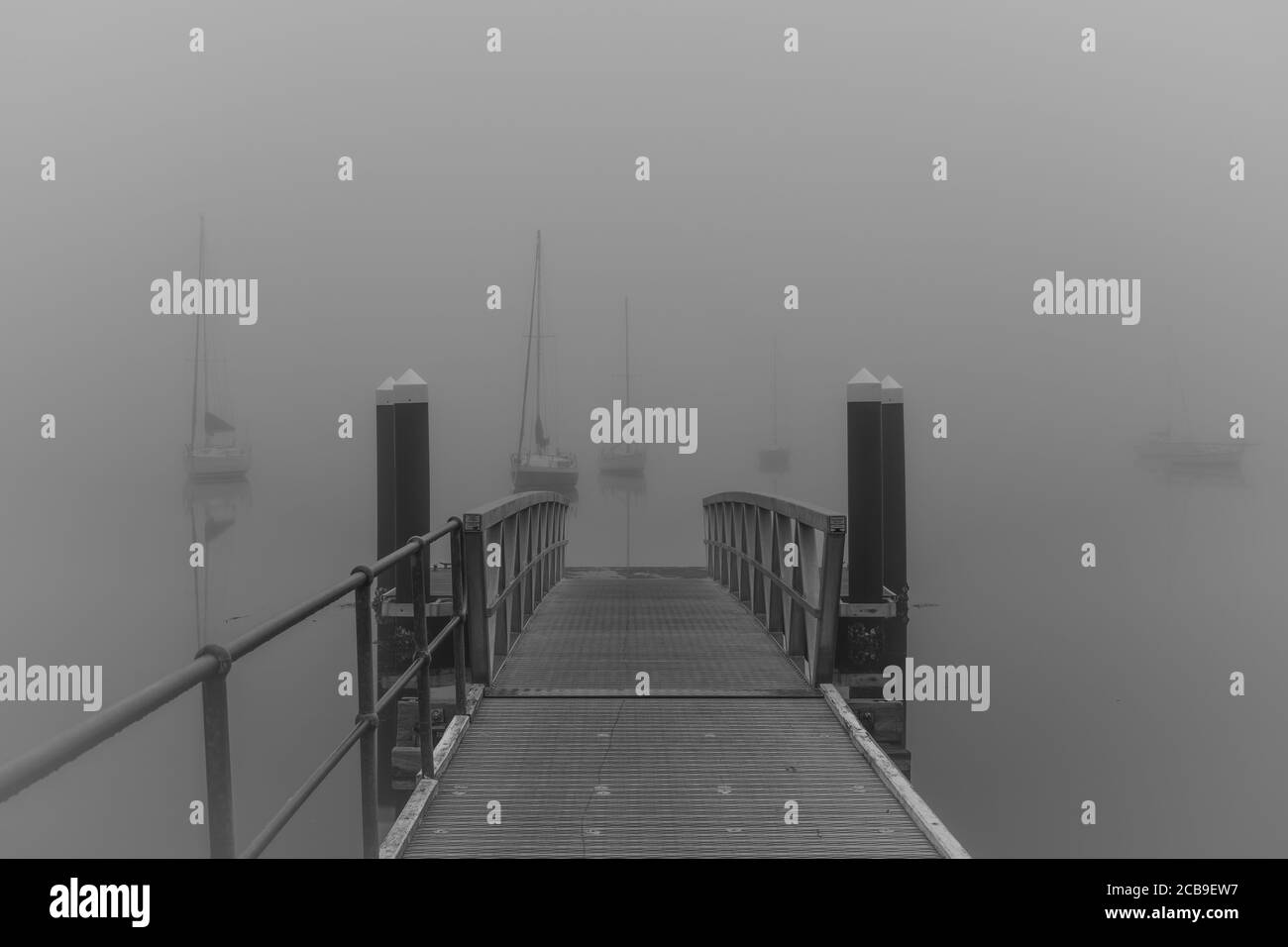 Enveloped in a dense fog boats appear over the wharf and through the ...