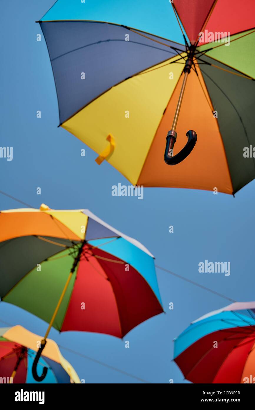 Rainbow colored umbrellas hanging in the sky. Summer travel. LGBT pride ...