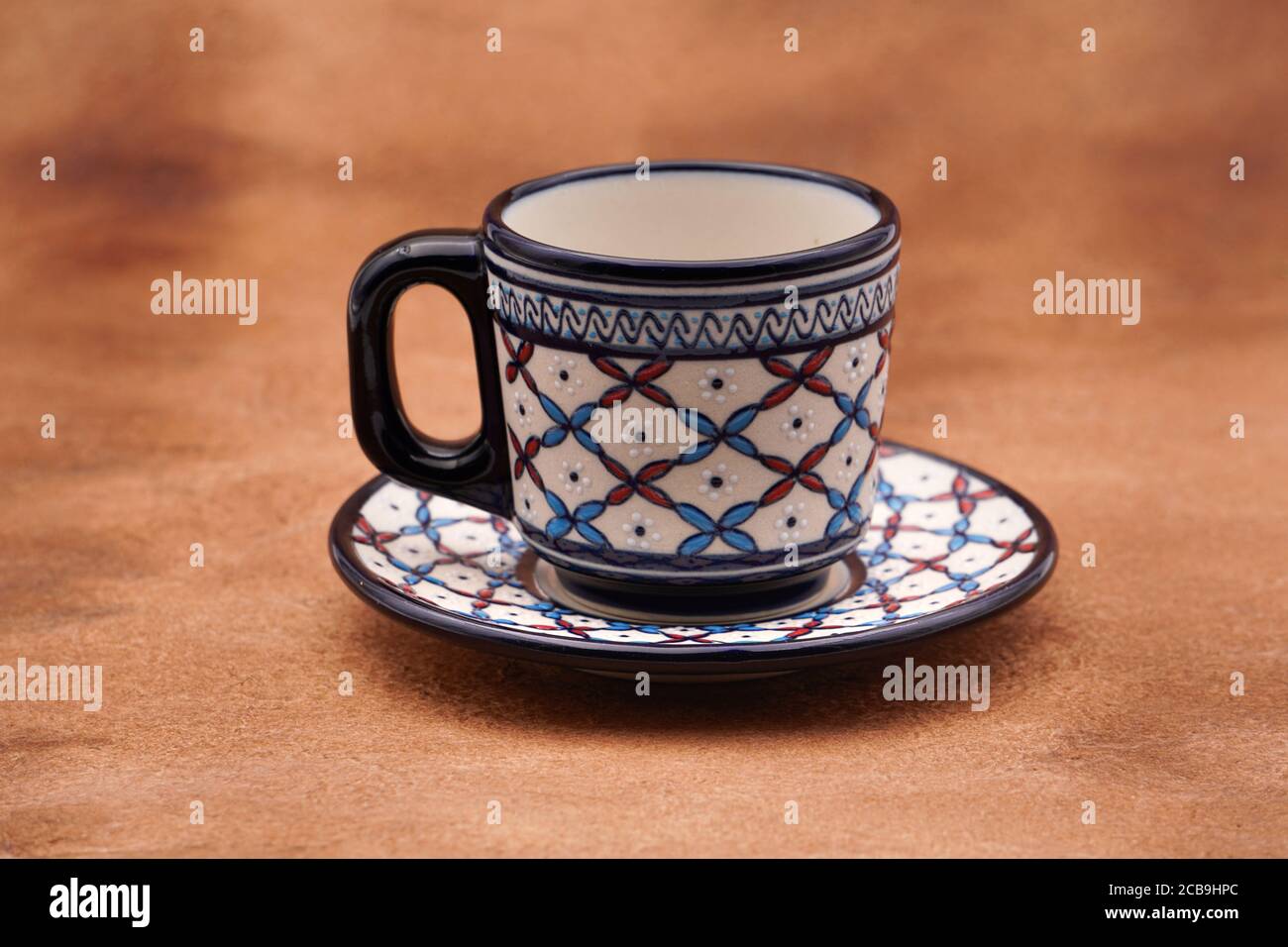 Cup and plate of coffee with a traditional design with brown background ...