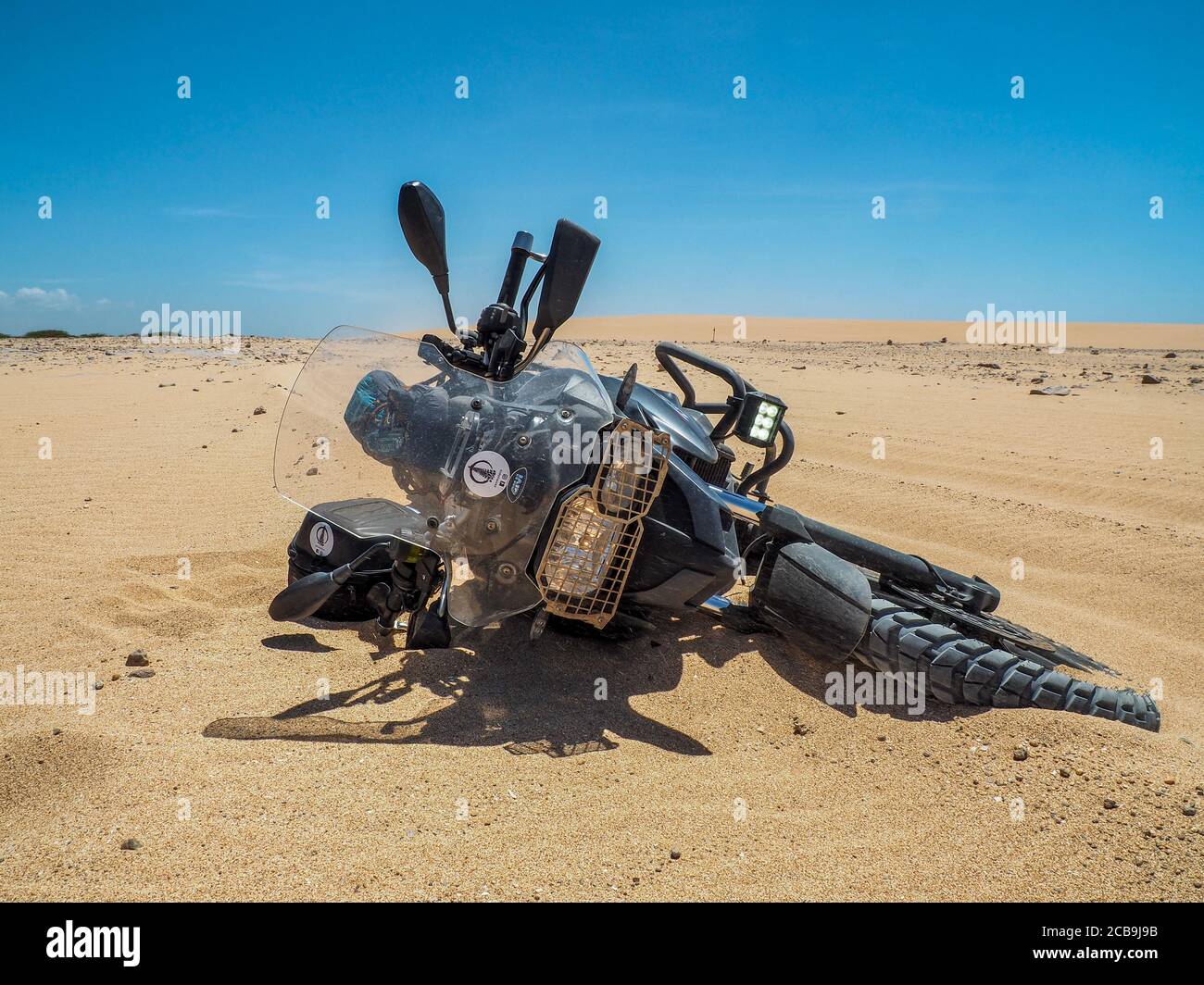 Motorbike lying on desert sand under a clear blue sky Stock Photo - Alamy