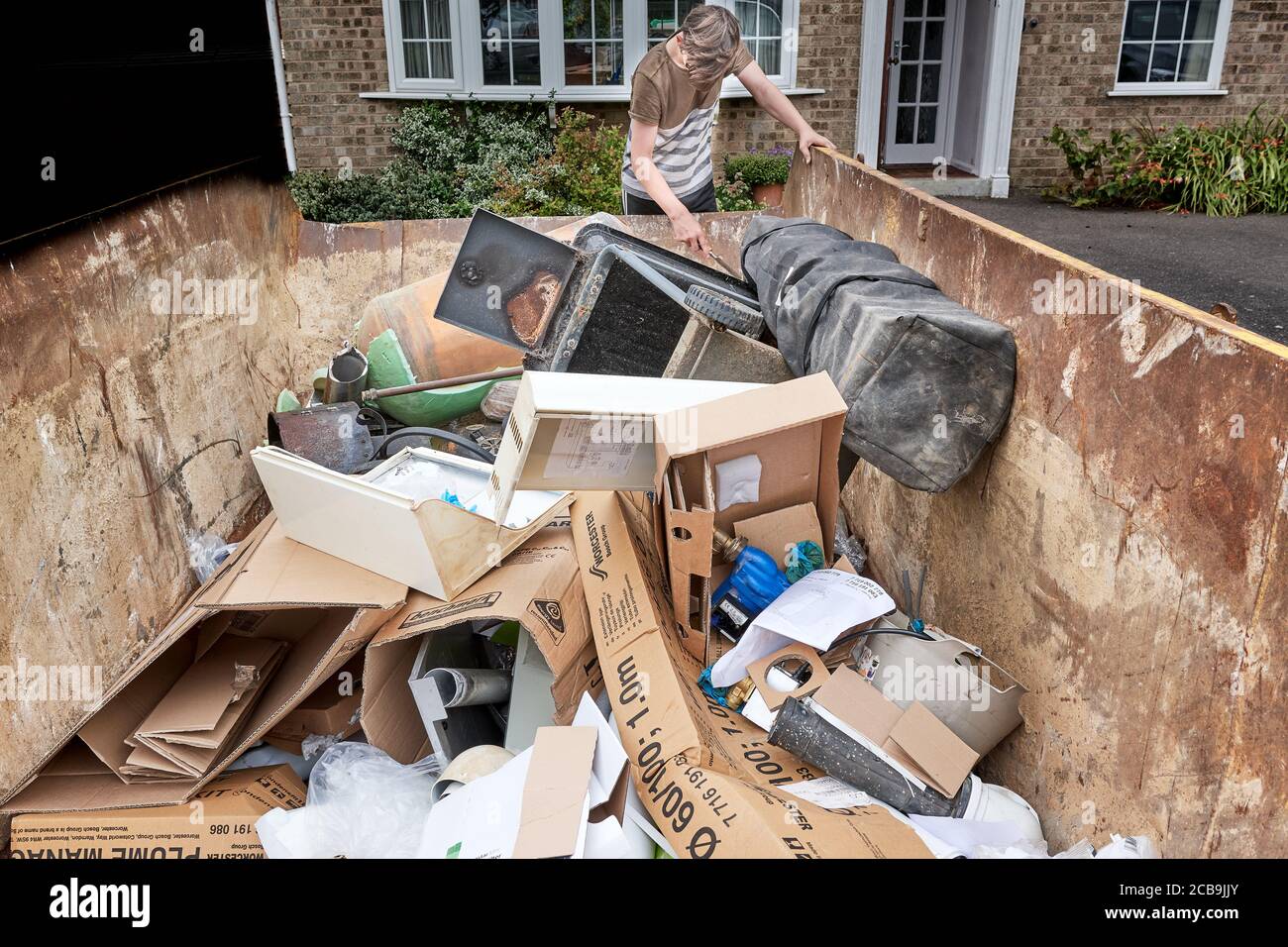 A teenage boy puts rubbish into a skip Stock Photo - Alamy