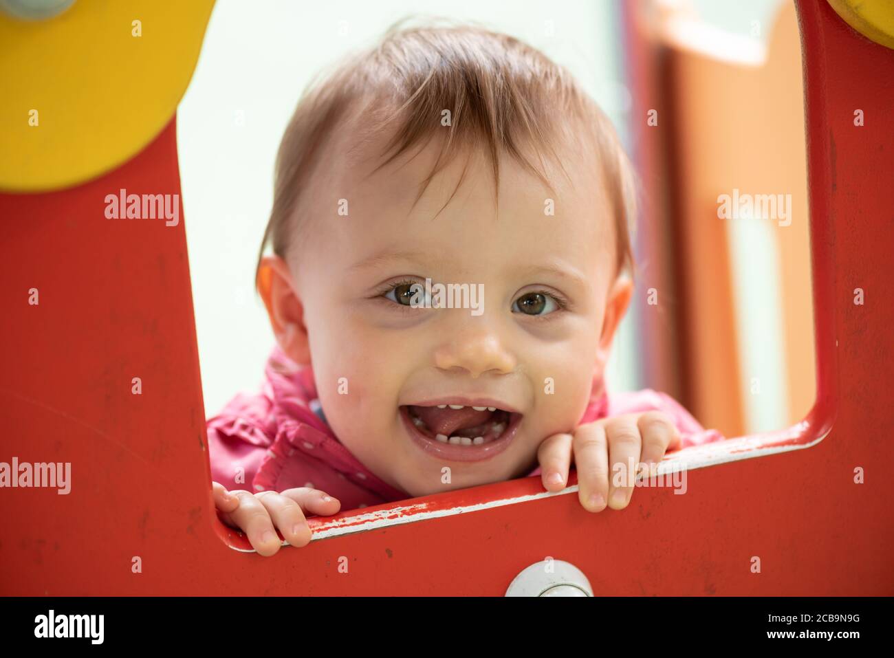 Cute baby girl having fun on a playground and looking at the camera ...