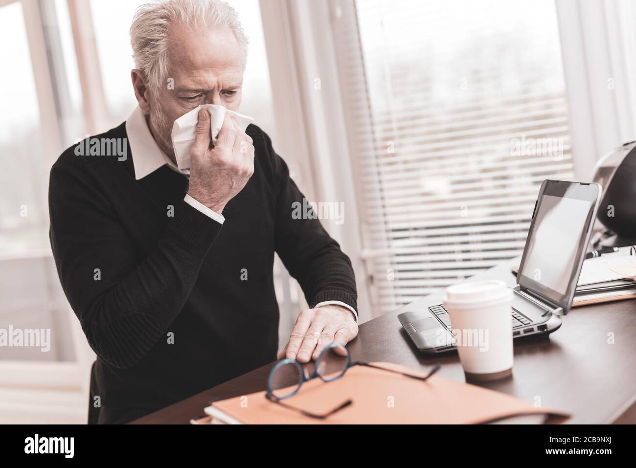 Senior businessman blowing his nose at office Stock Photo - Alamy